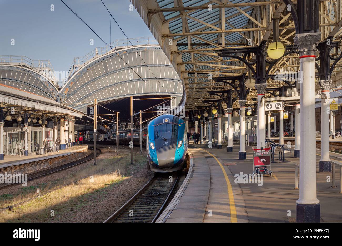 Railway station platform with a train alongside. Overhead is an ...