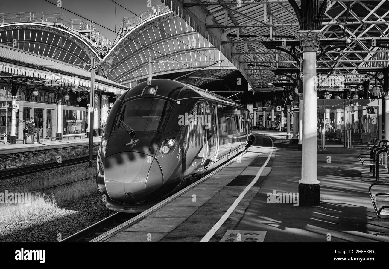 Railway station platform with a train alongside. Overhead is an ...