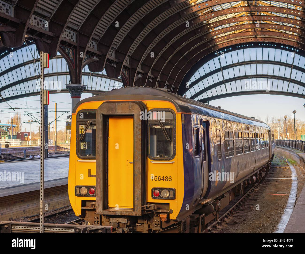 Railway station platform with a train alongside. Overhead is an ...