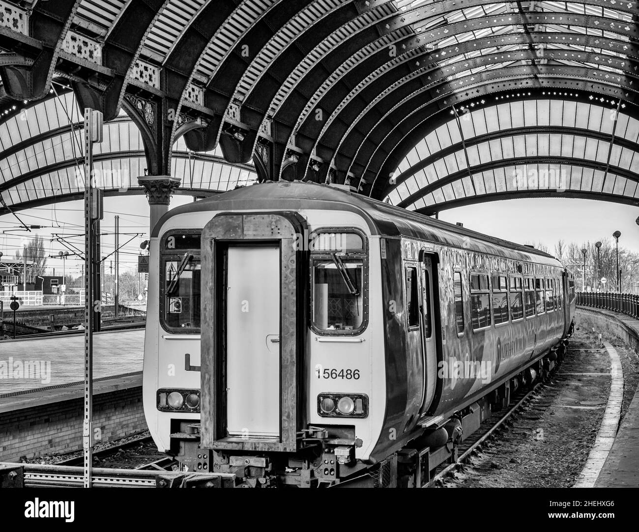 Railway station platform with a train alongside. Overhead is an ...