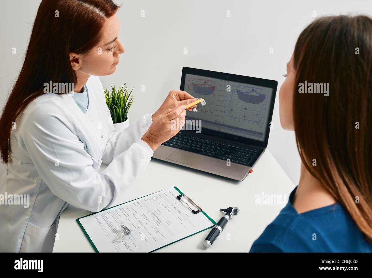 Audiologist shows a hearing aid to woman patient for treatment of ...