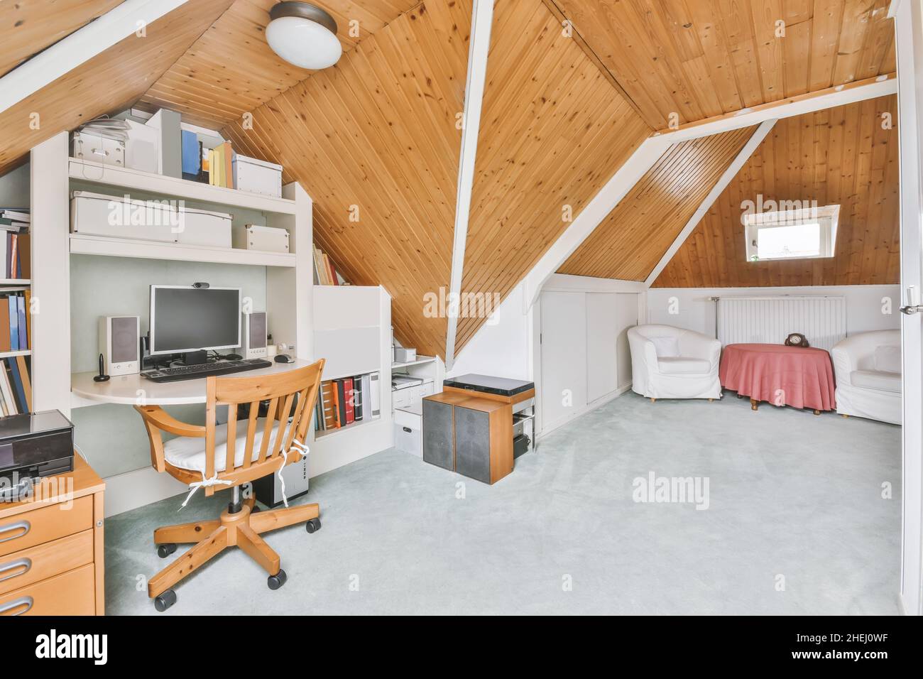 Cozy furnished attic with a high wooden ceiling and light gray carpet ...
