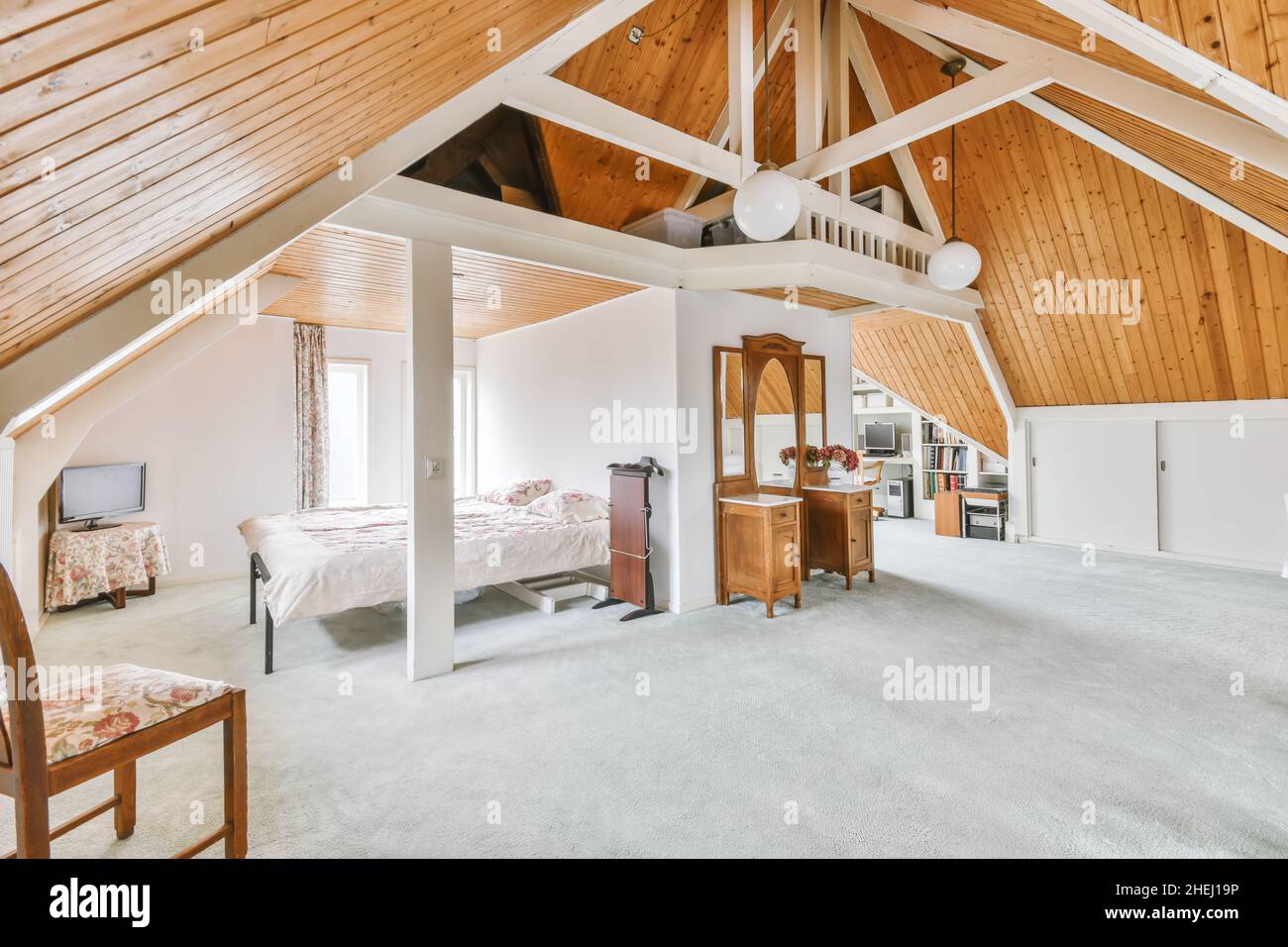 Cozy furnished attic with a high wooden ceiling and light gray carpet ...
