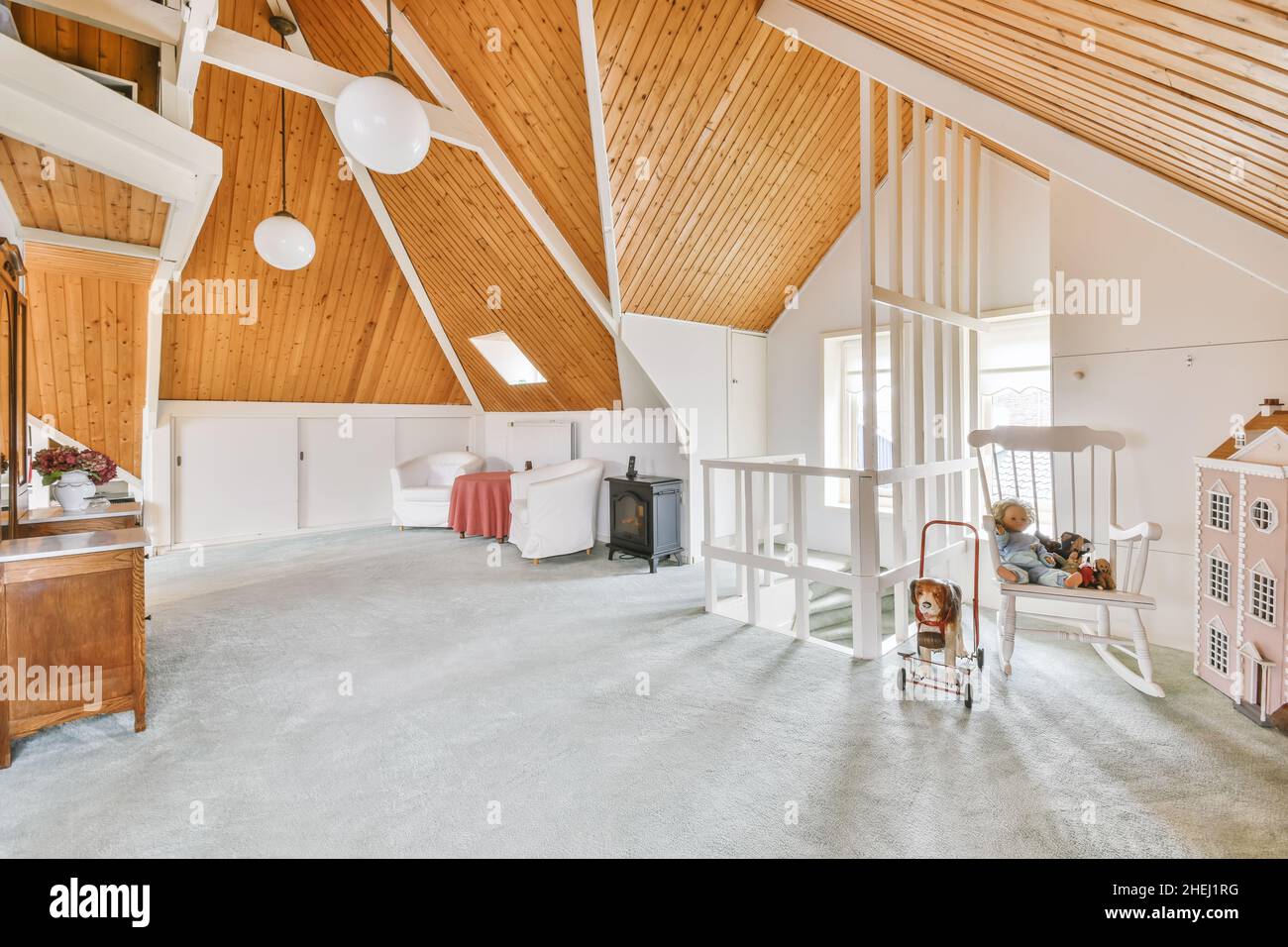Cozy furnished attic with a high wooden ceiling and light gray carpet ...