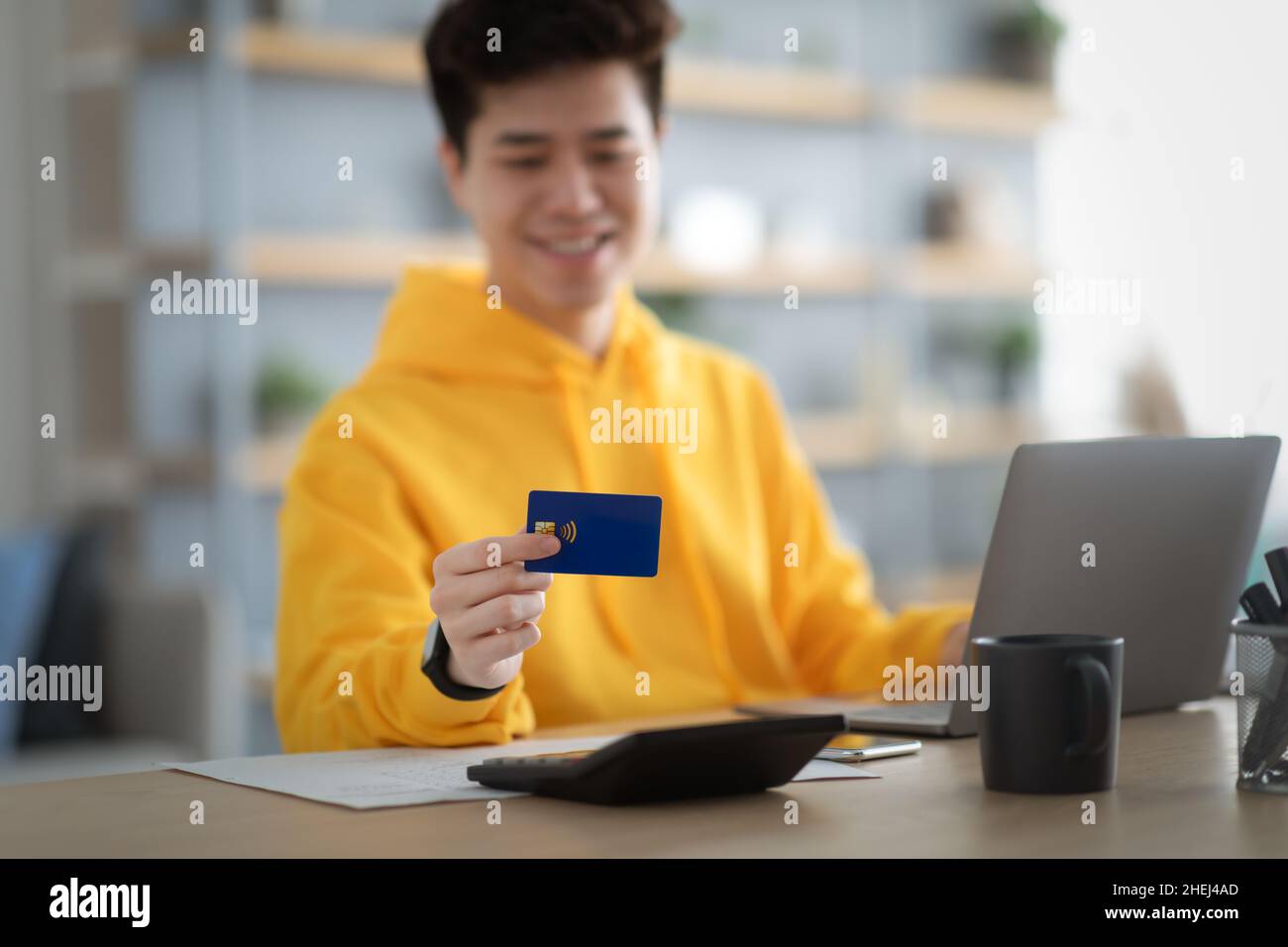 Smiling asian guy showing using credit card at home Stock Photo - Alamy