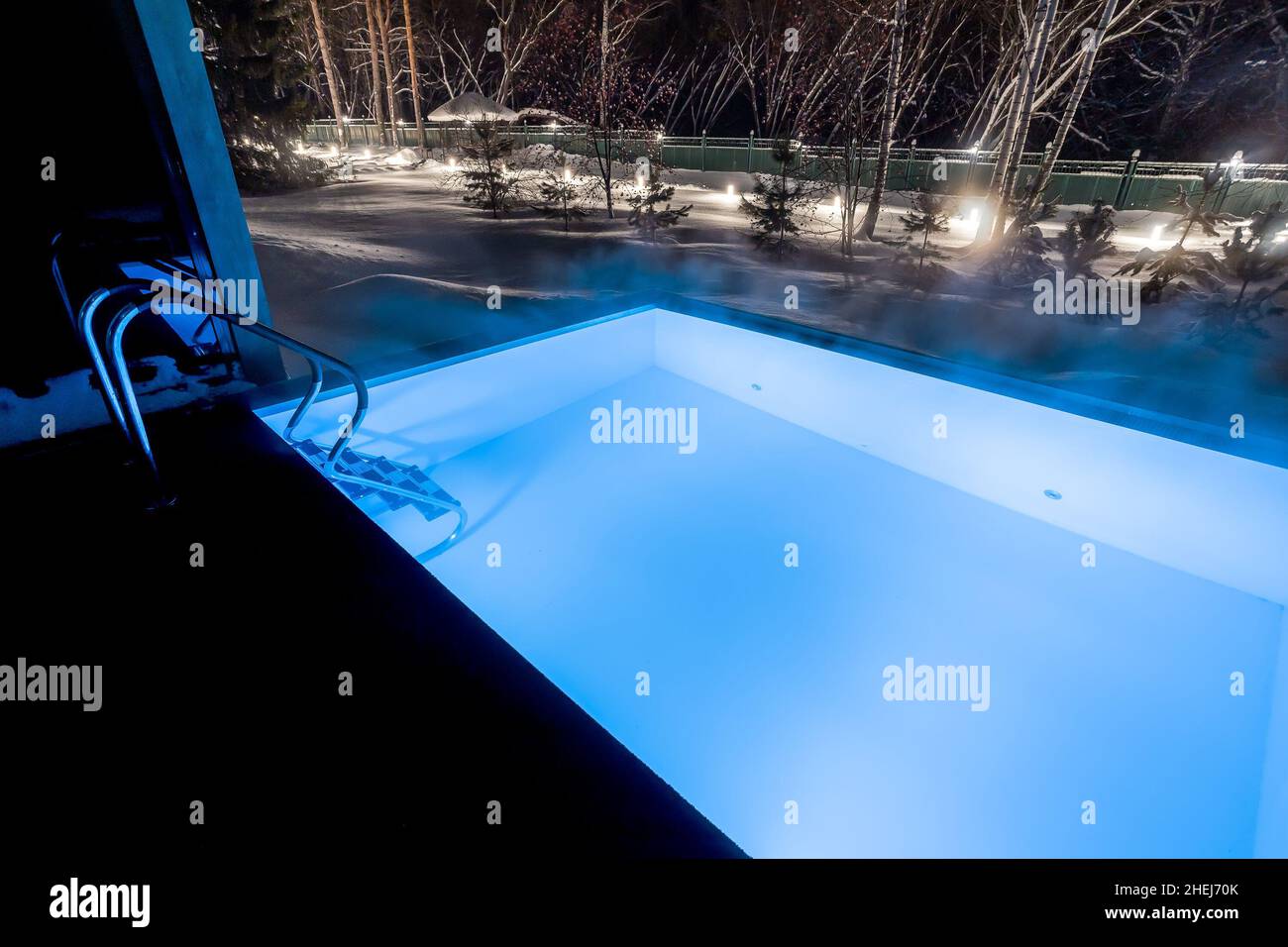 Outdoor warm swimming pool with blue water and wooden Russian bath in ...