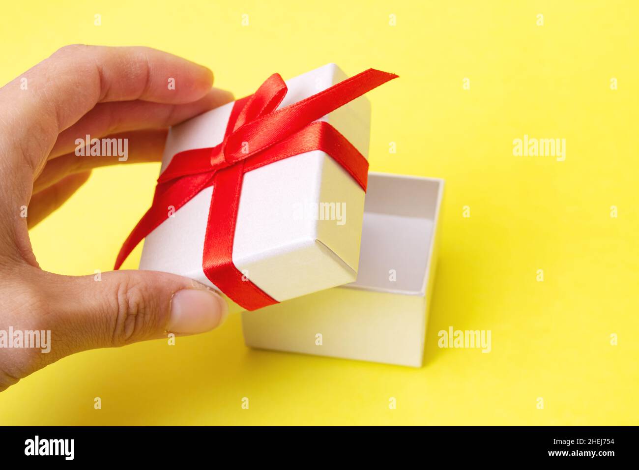 Hand opens a white box with a gift on a yellow background Stock Photo ...