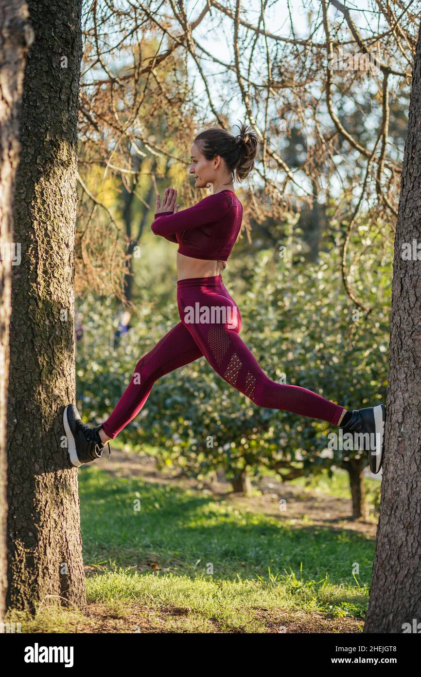 Training pose between trees. Beautiful girl in sportswear doing yoga on ...