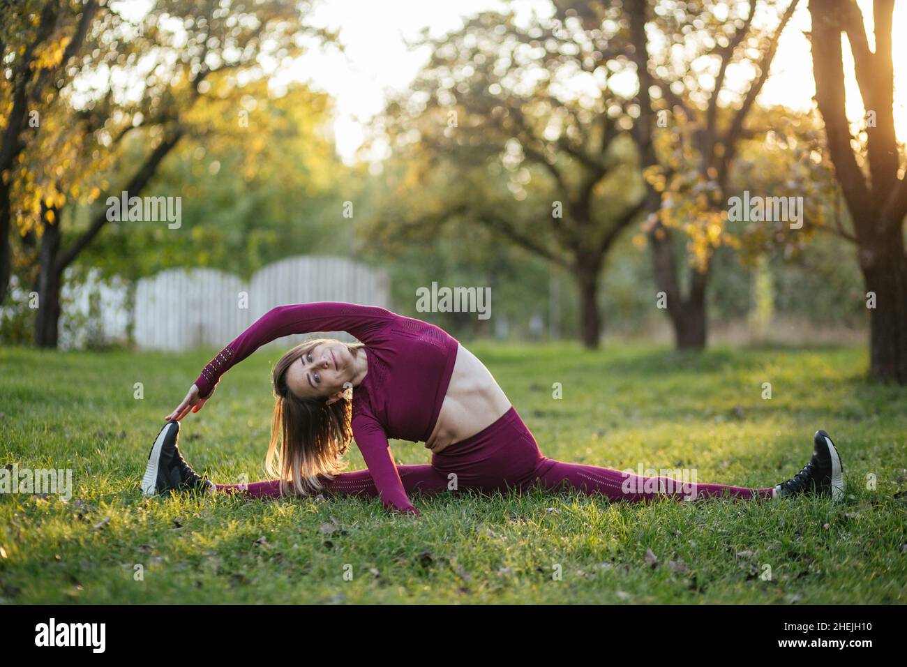 Split-leg on sunset. Girl in red sportswear doing yoga pose in the ...