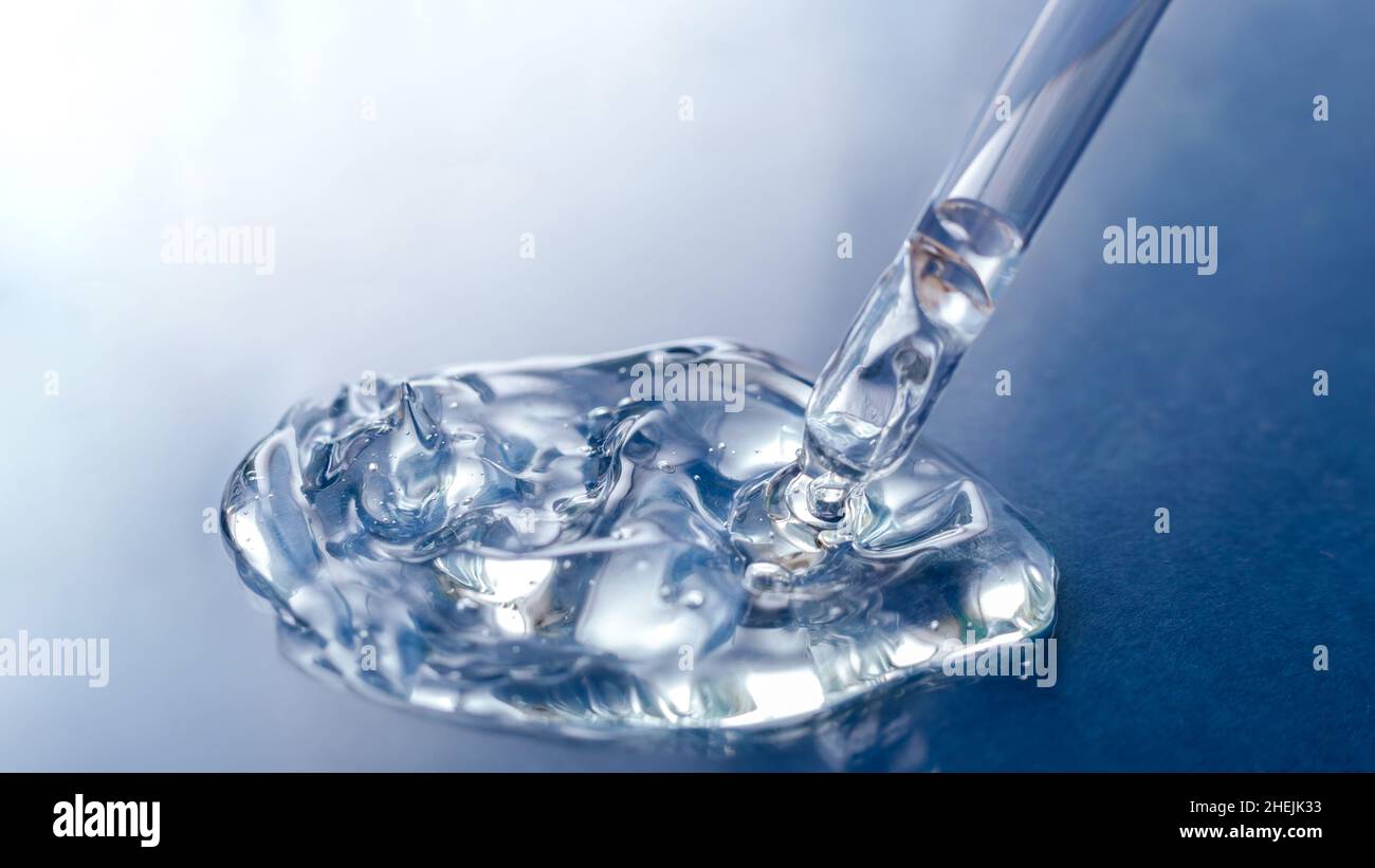 Liquid transparent gel serum swatch with pipette on blue color glass ...