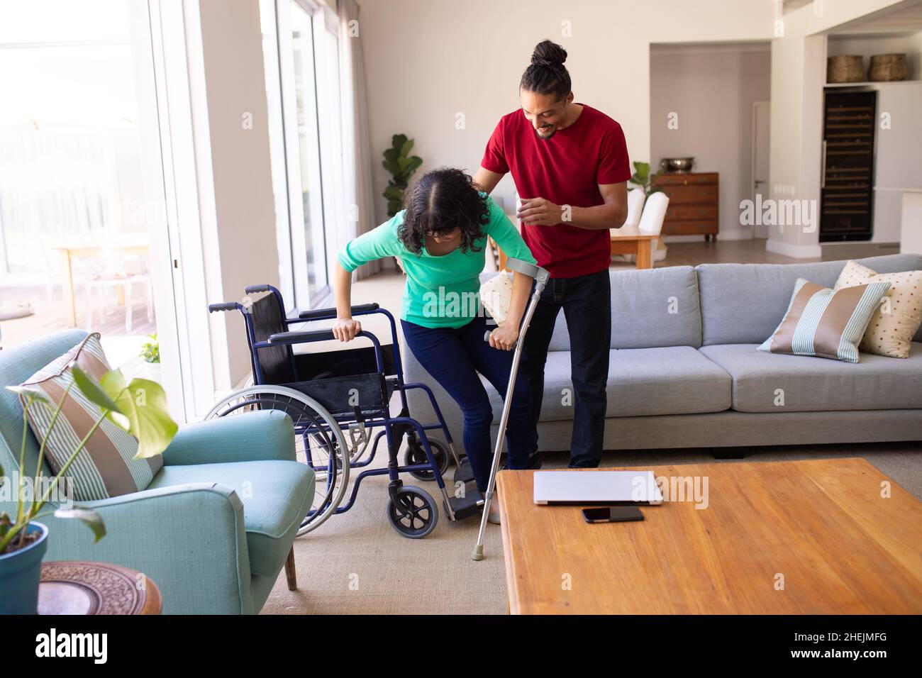 African American Man Helping His Disabled Wife To Sit On The Wheelchair