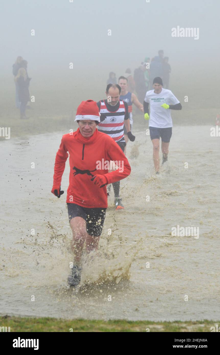 group of runner going through water feature at cross country race ...