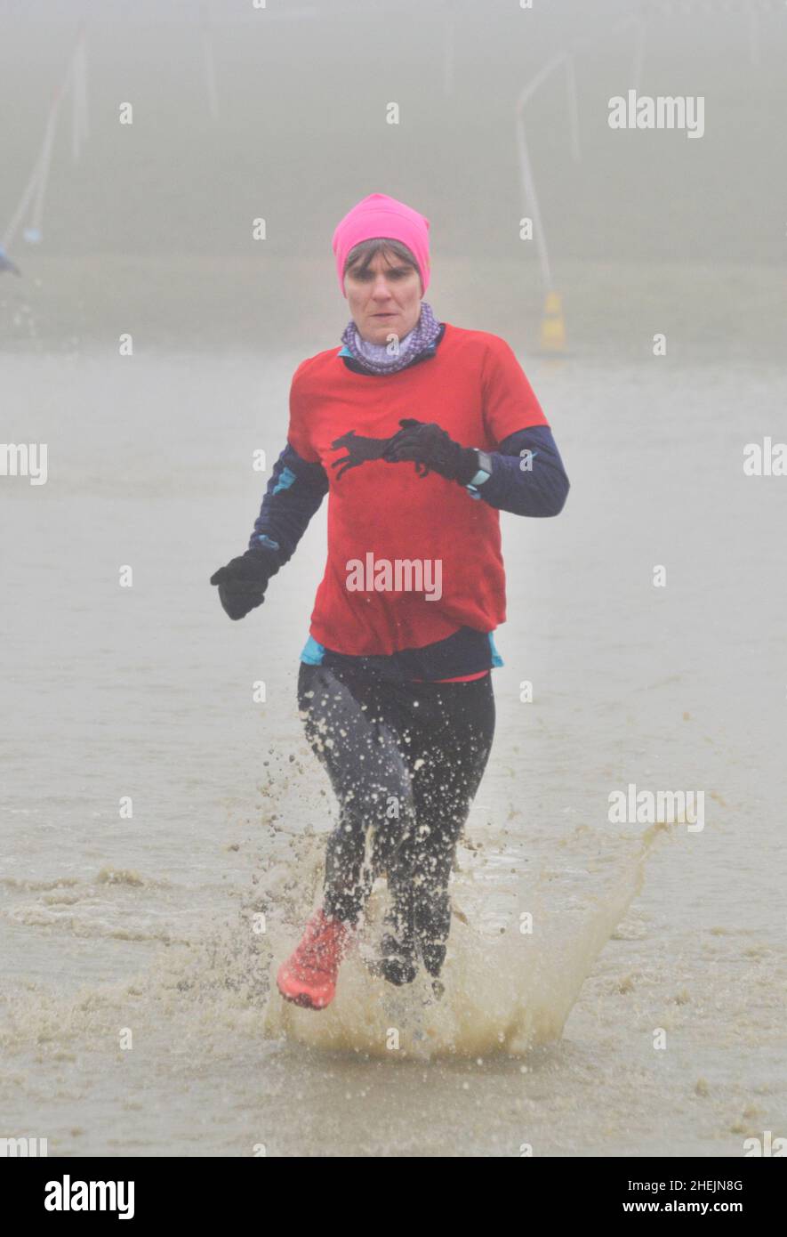 woman club runner running through water feature in cross country race ...