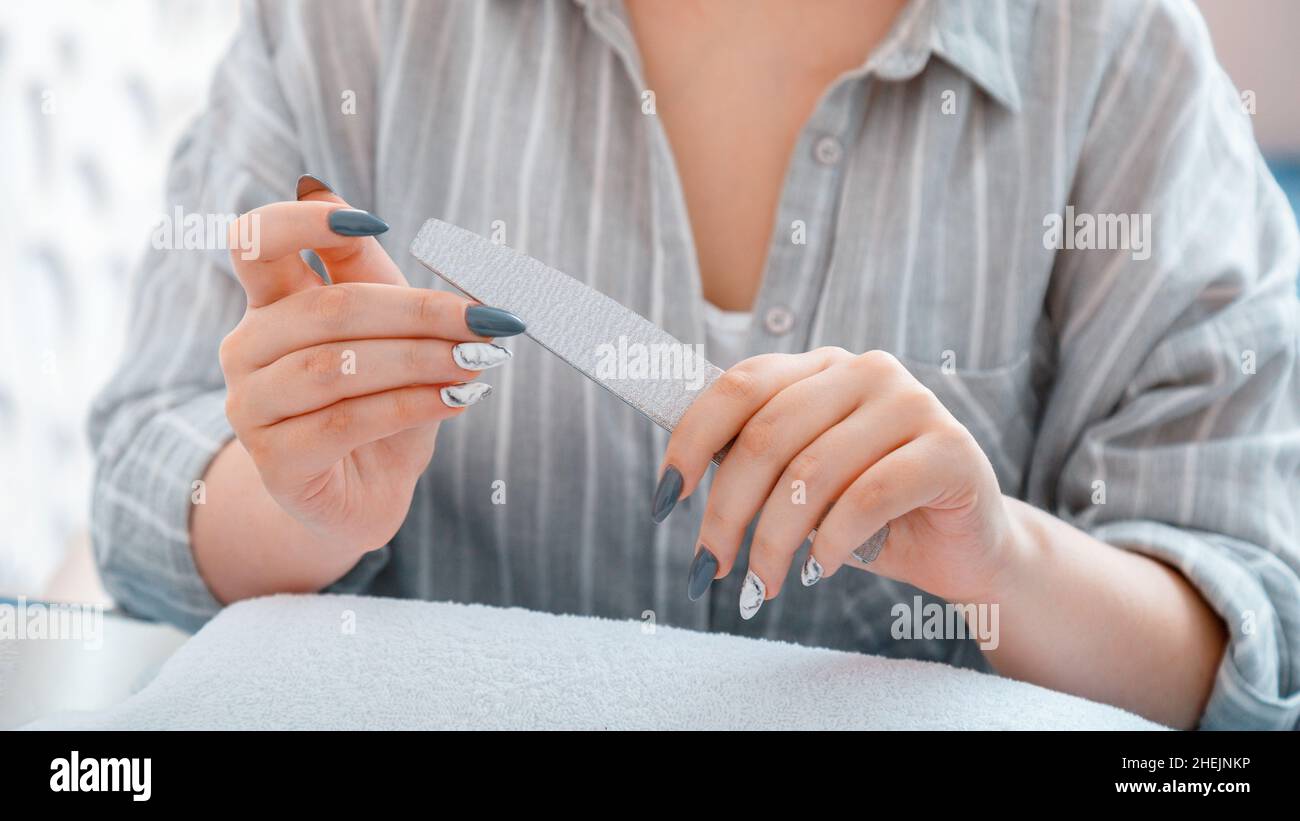 Manicure file in female hands. Woman makes herself manicure, beauty ...