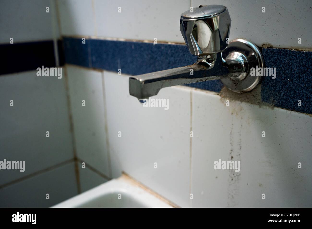 dripping, drop of water comes out of a dirty corroded metal faucet on a ...