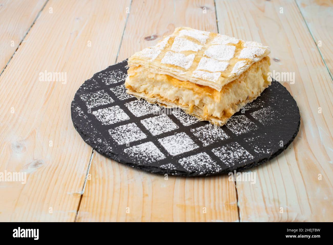 cremeschnitte or cremsnit cake on a square black stone tile texture ...