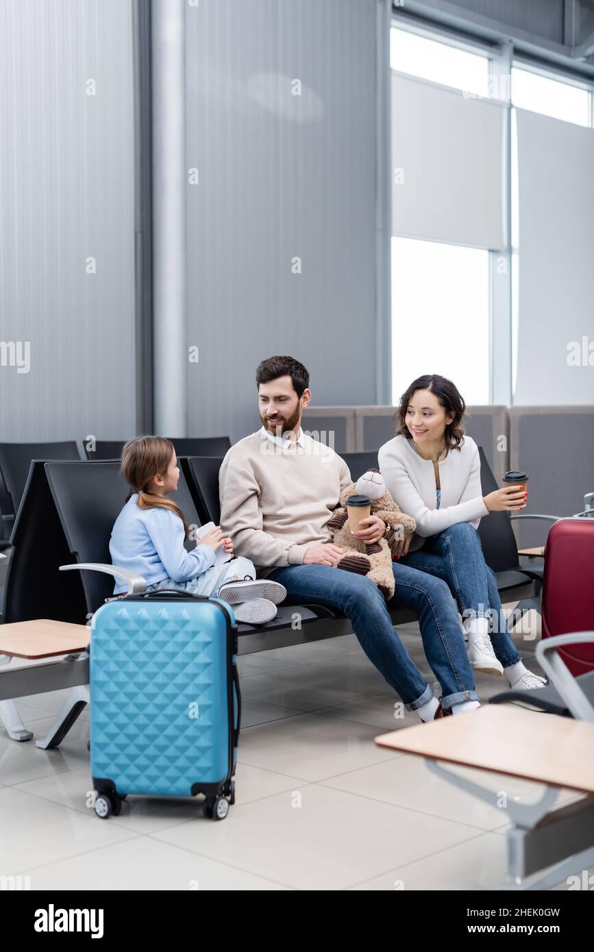 happy parents looking at daughter with smartphone in airport Stock ...