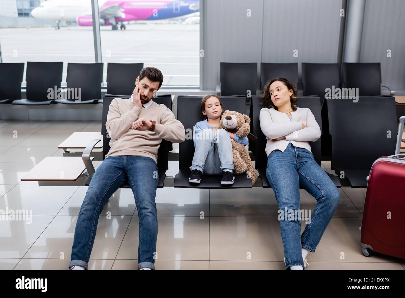 bored man looking at watch near daughter and wife in airport Stock ...