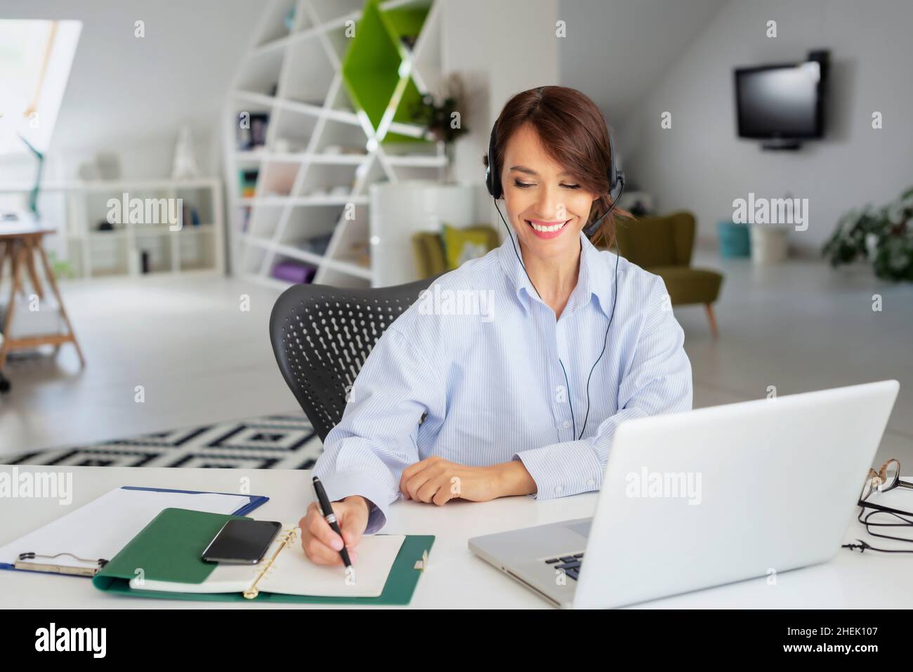 Customer service assistant wearing headset while sitting behind her ...
