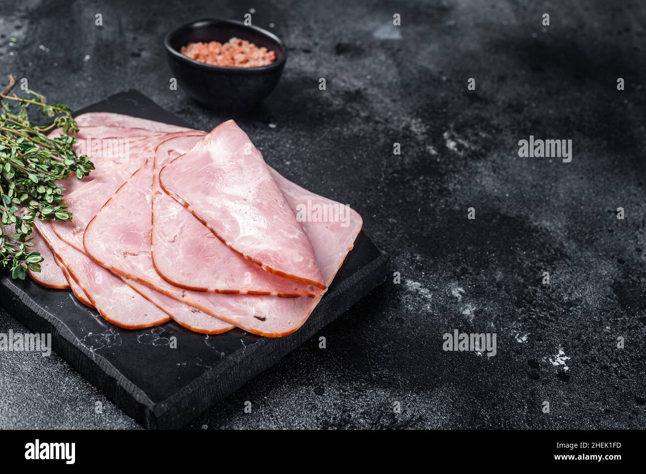 Squared slices of lean pork ham. Black background. Top view. Copy space ...