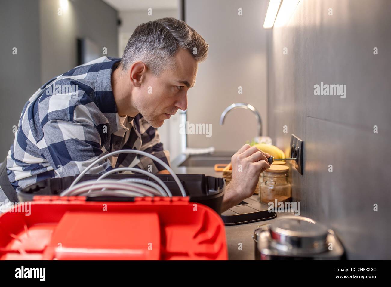 Profile of man touching socket on wall with screwdriver Stock Photo - Alamy