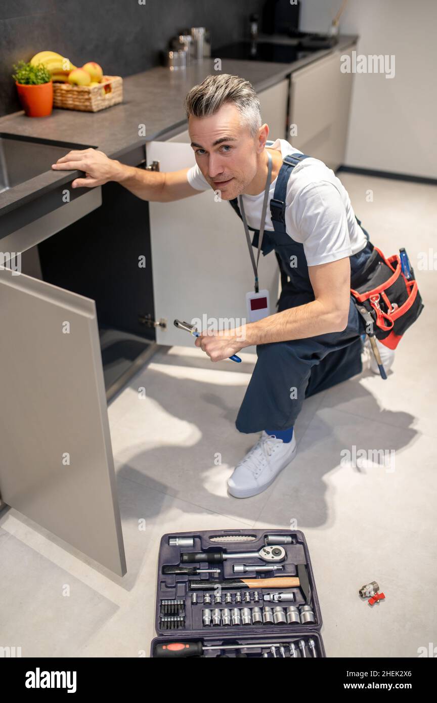 Top view of man crouching near sink looking at camera Stock Photo - Alamy