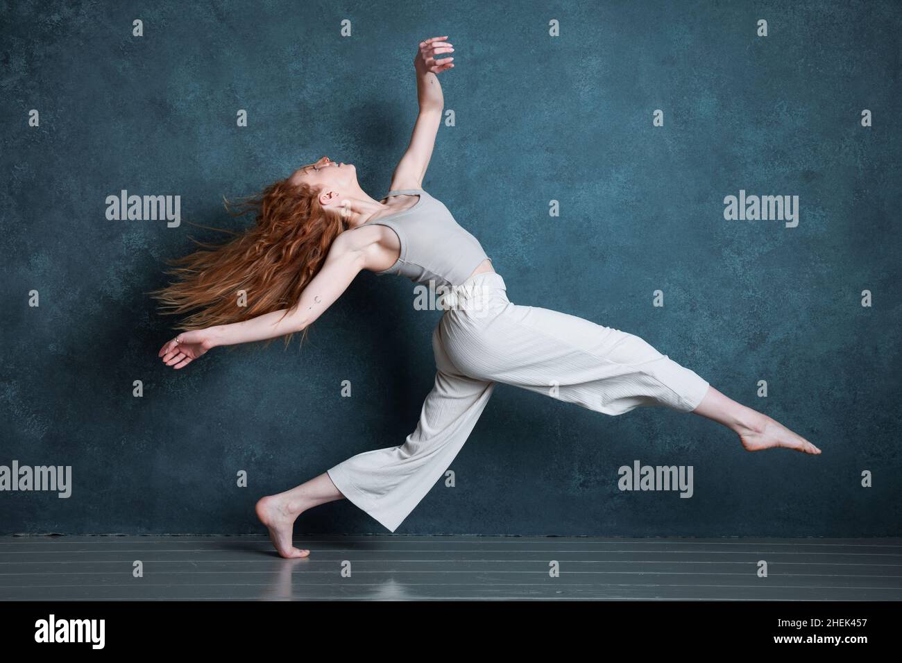 Petitie dancer with red auburn hair dancing against grey backdrop Stock ...