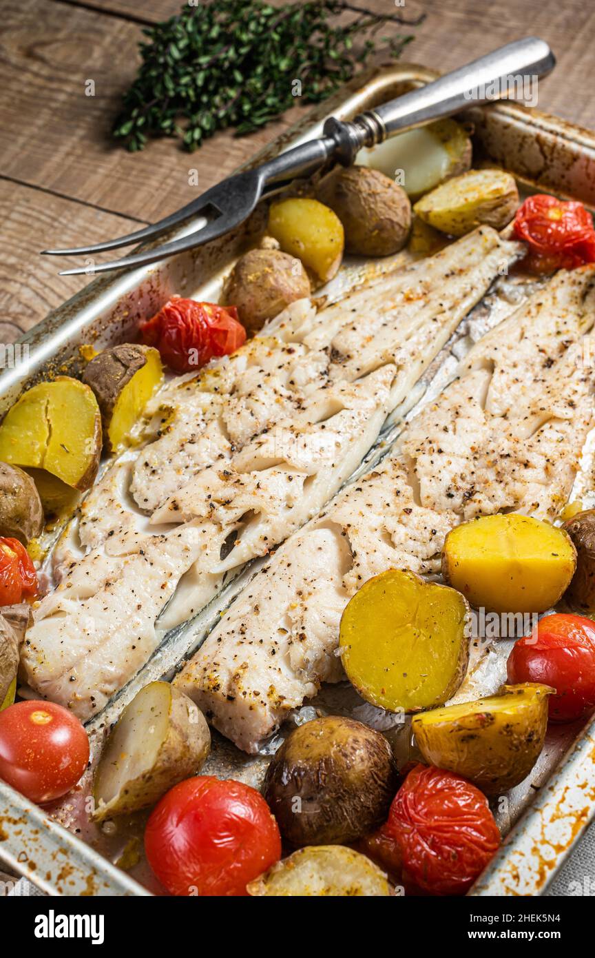Hake fish fillet, roasted fish meat with tomato and potato. Wooden ...