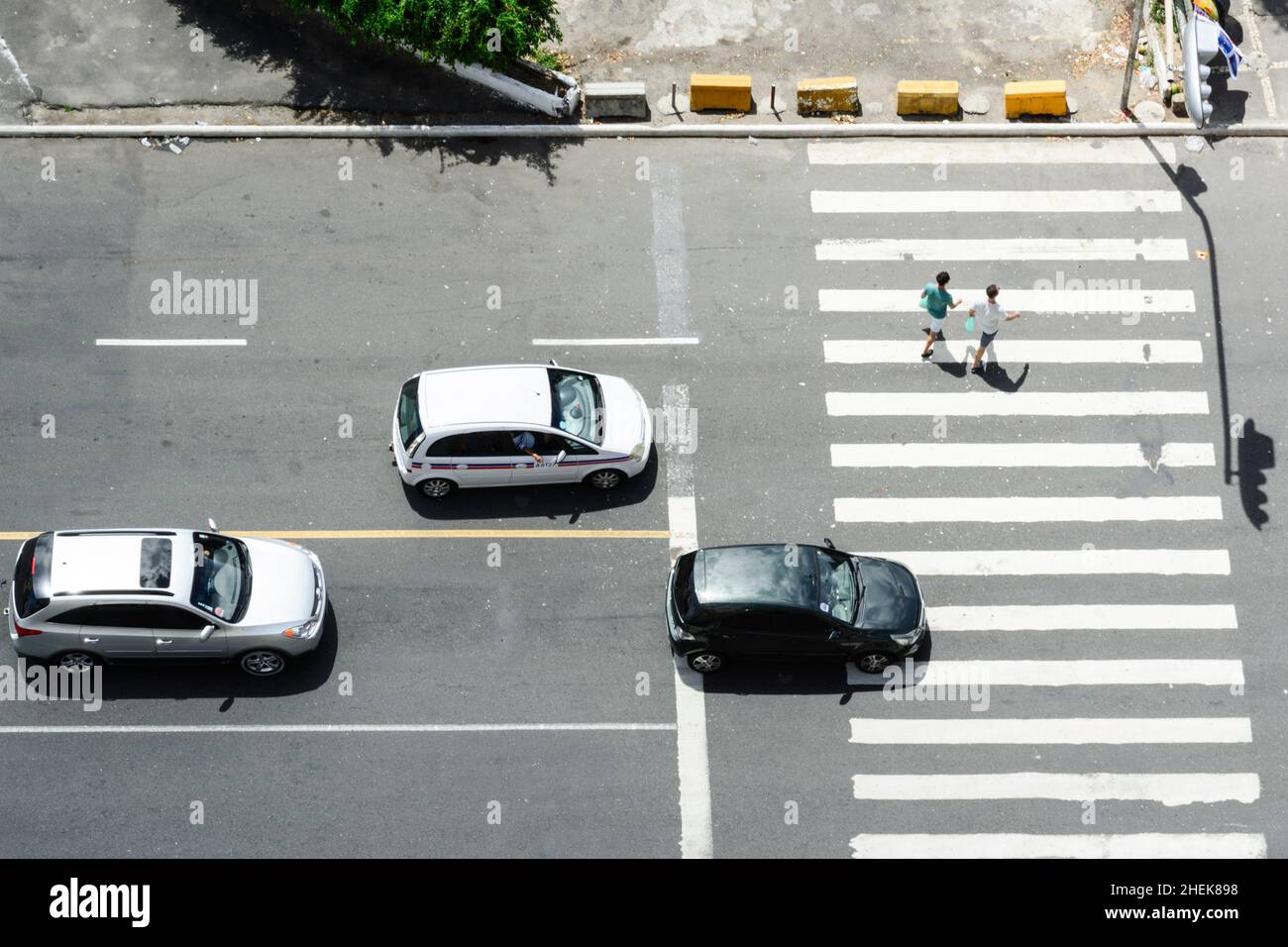 Three cars stopped and two people crossing at the crosswalk Stock Photo ...