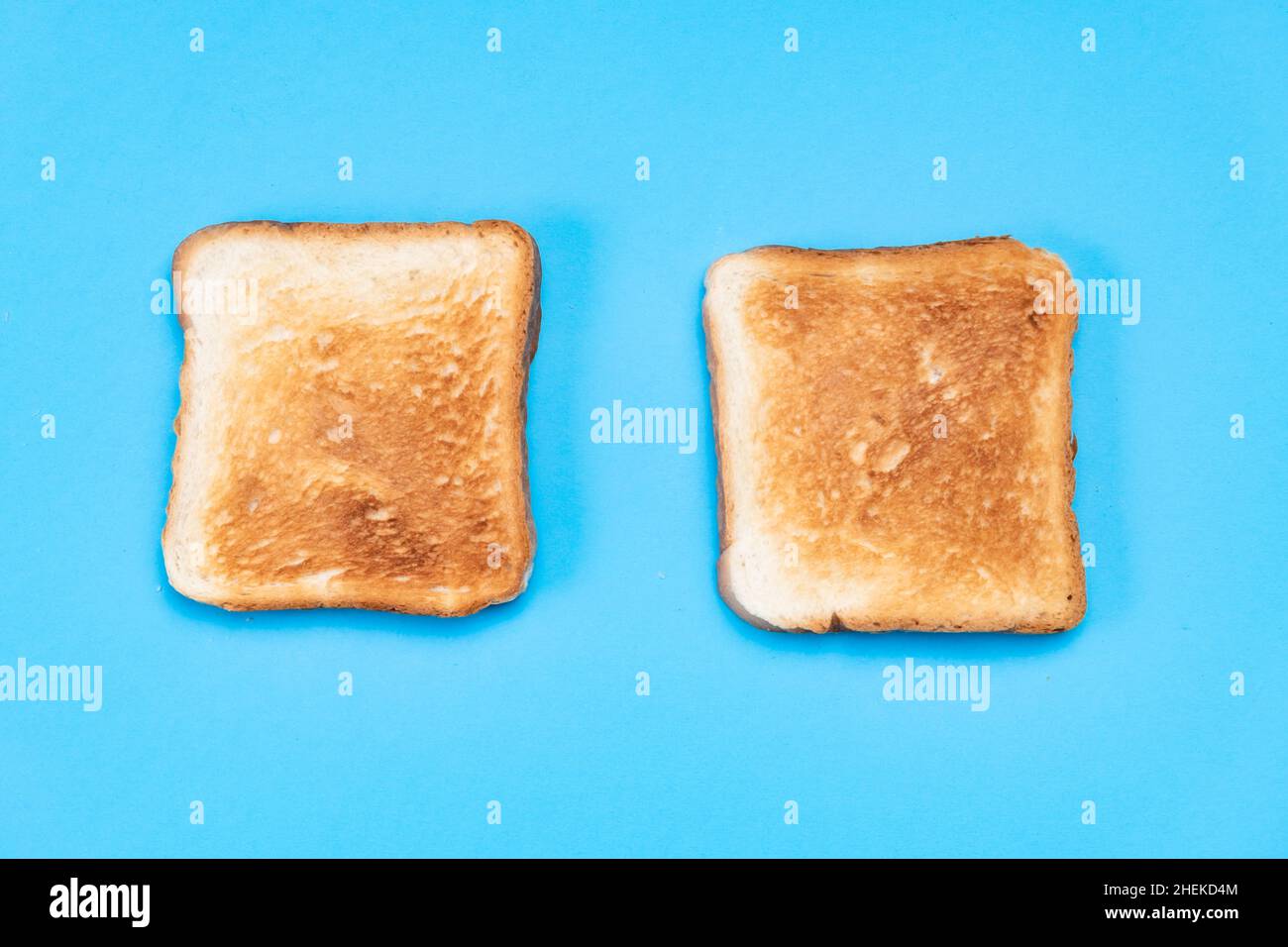 Two pieces of toasted toast on a blue background. Food concept Stock ...