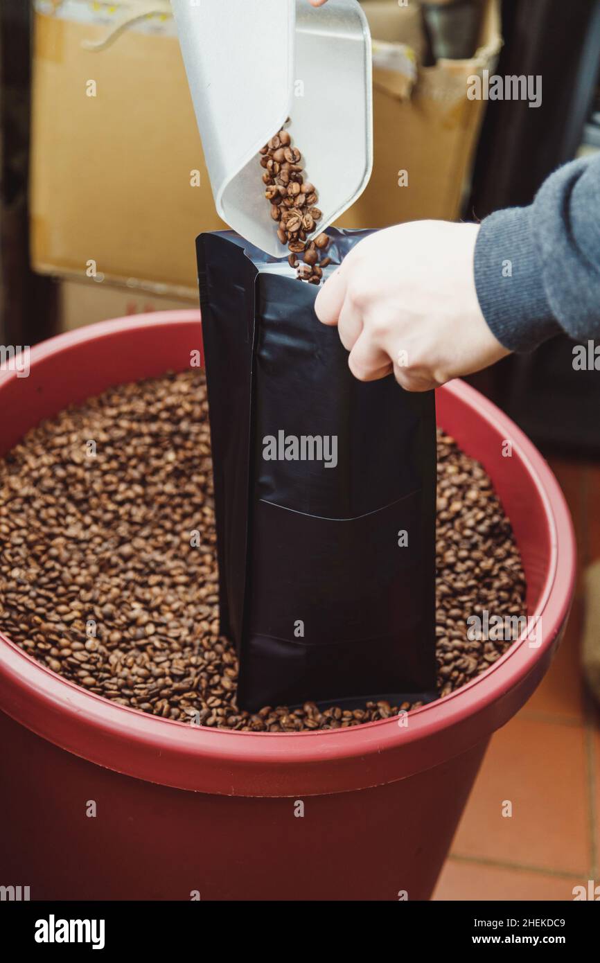 Green coffee beans pour into package for sale. Taking roasted beans ...