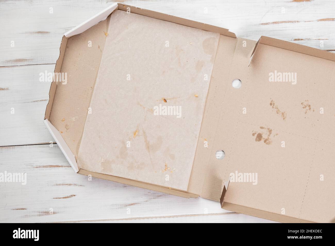 Empty open pizza box. White wooden background. Eaten pizza. Top view ...