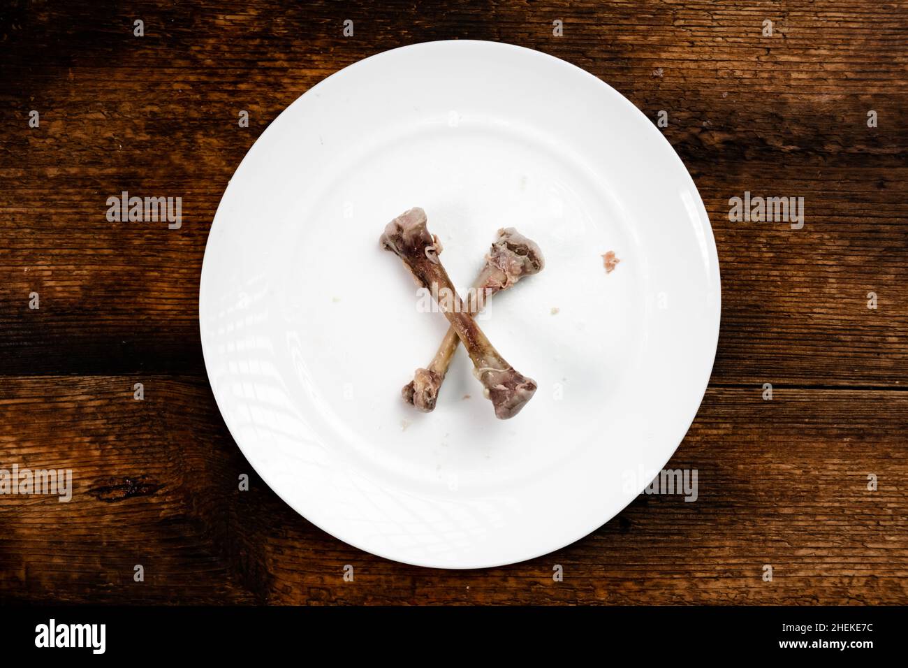 Chicken bones on a white plate. Dark wooden background. End of the meal ...