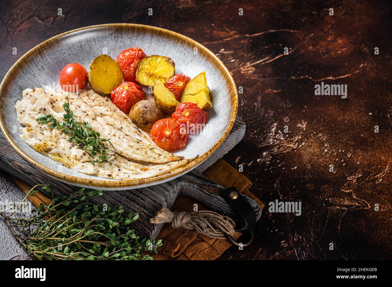 Roasted Pollock fish fillet in plate with garnish tomato and potato ...