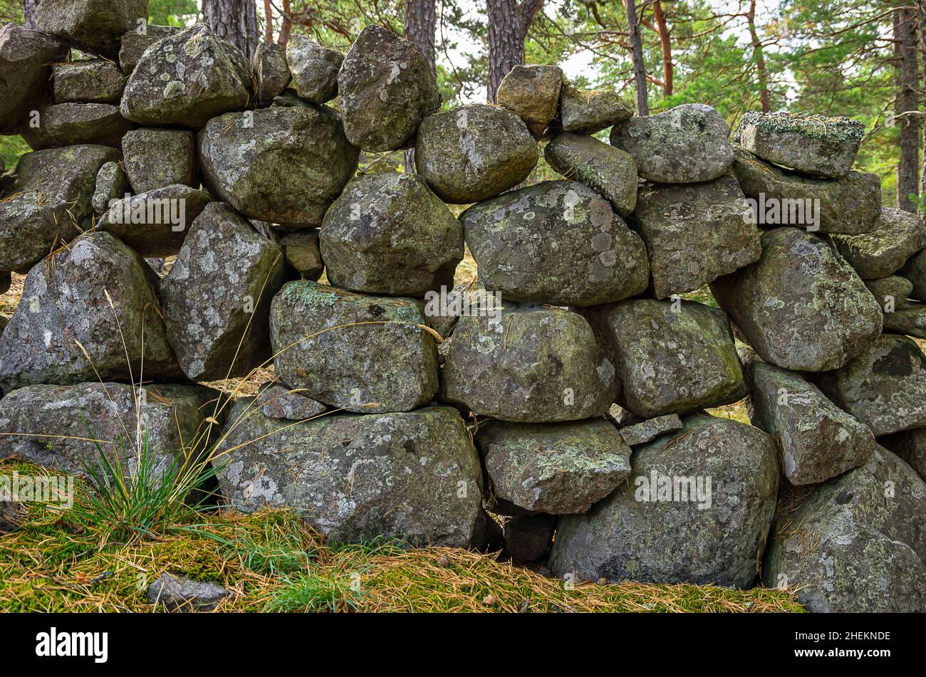 A wall of mossy fieldstones marks the boundary of a plot of land in a ...