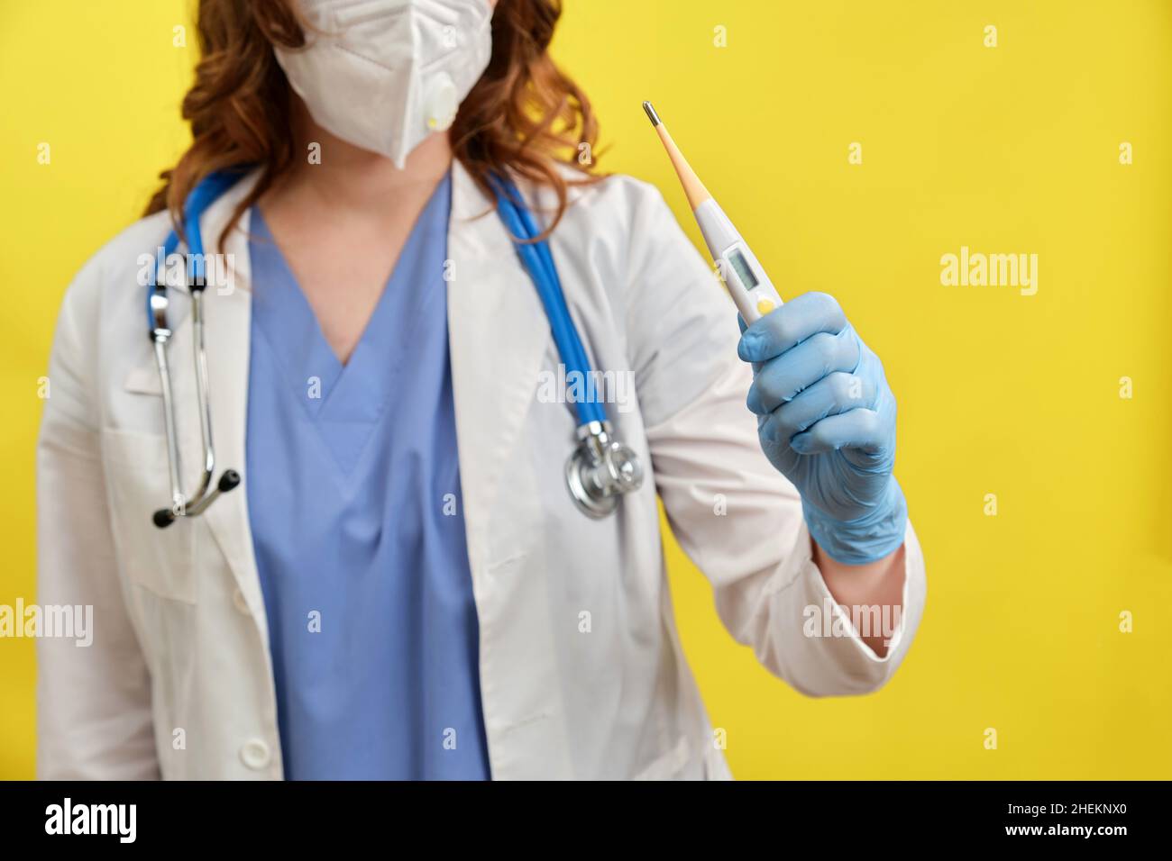 A female doctor holds an electronic digital thermometer in her hand ...