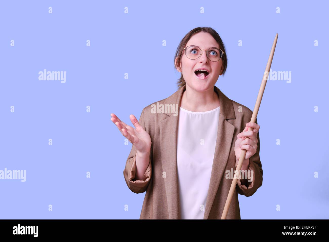 Happy woman teacher with pointer on studio blue background, copy space ...