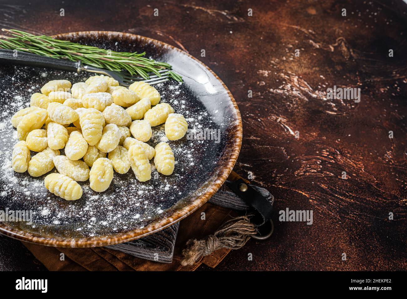 Italian gnocchi dumplings, Raw potato gnocchi on plate with thyme. Dark ...