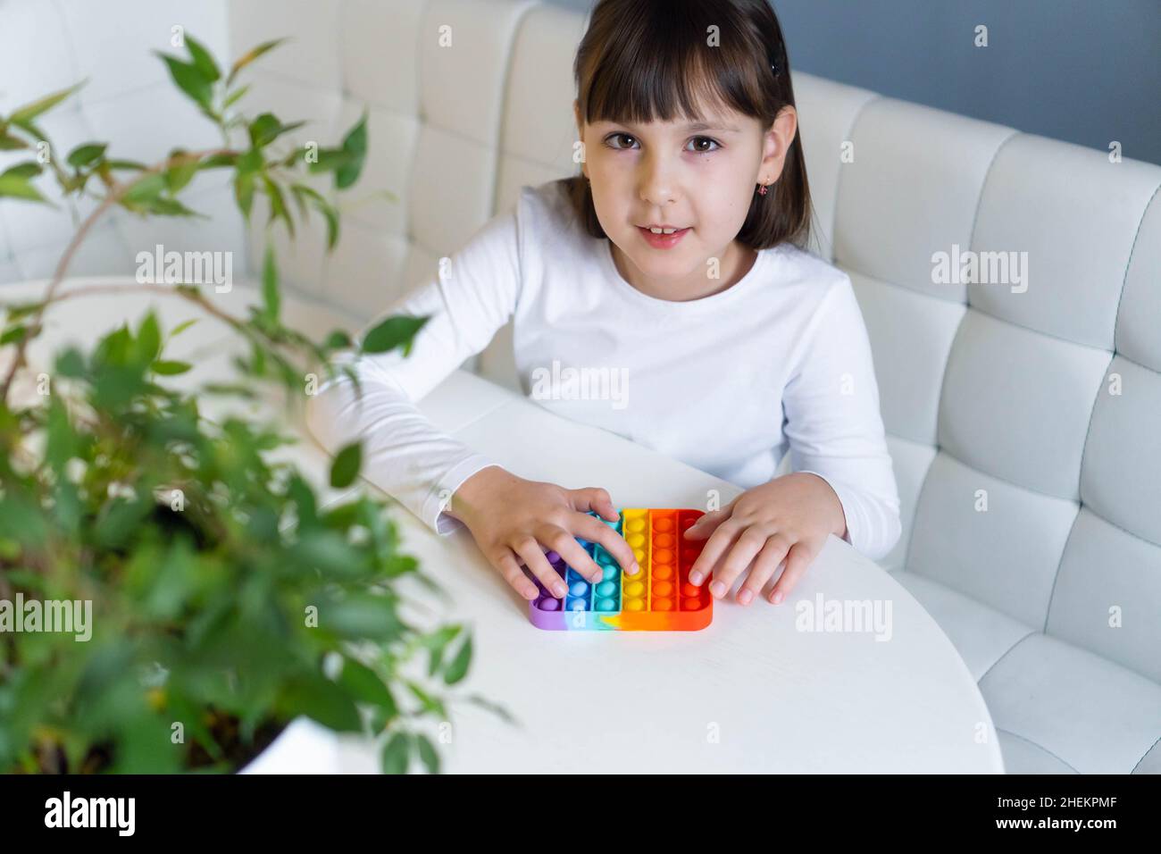 Baby girl playing with rainbow pop it fidget. The concept of mental ...