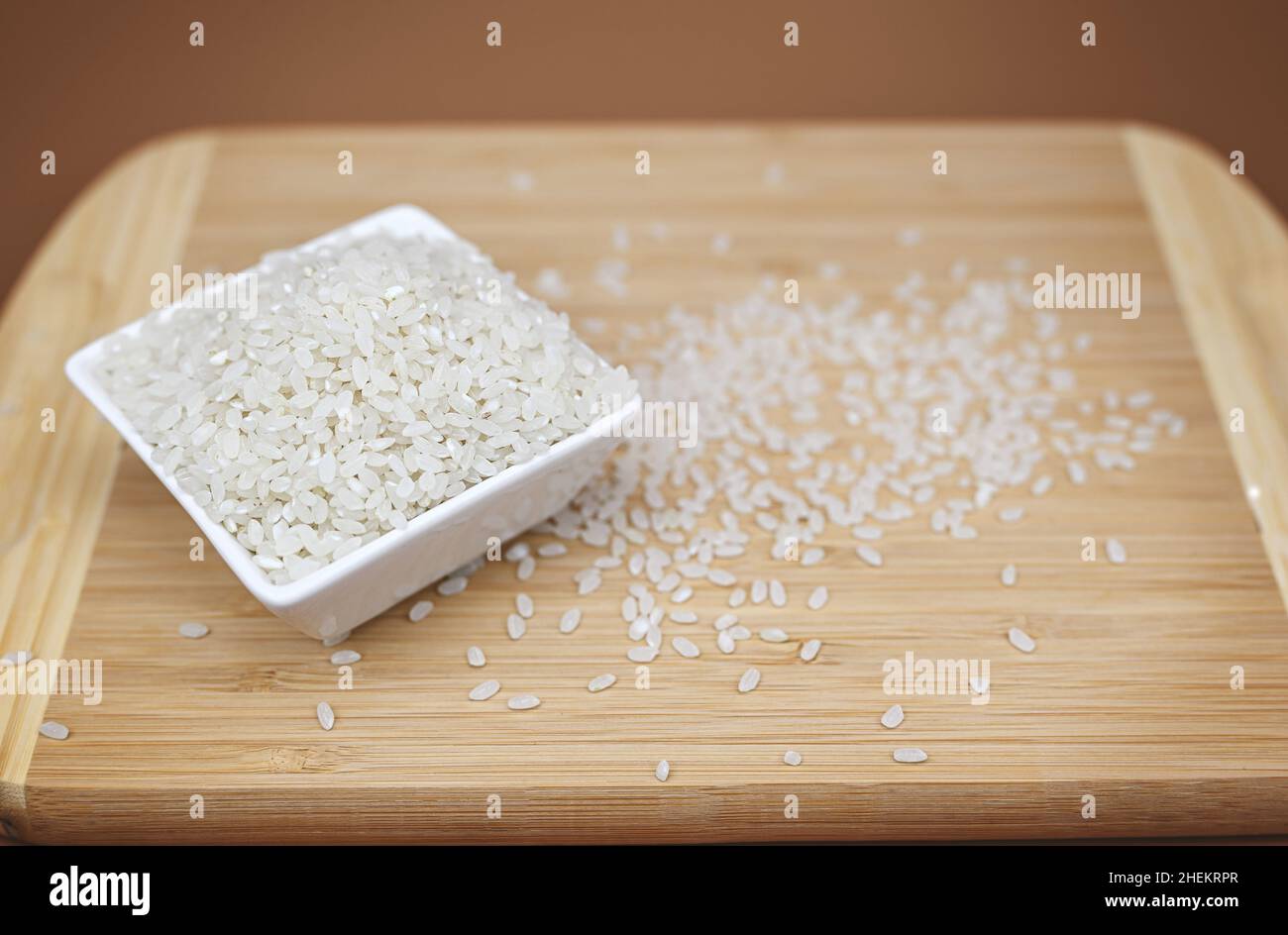 Raw white rice in a ceramic bowl. Beige background, free space for text ...