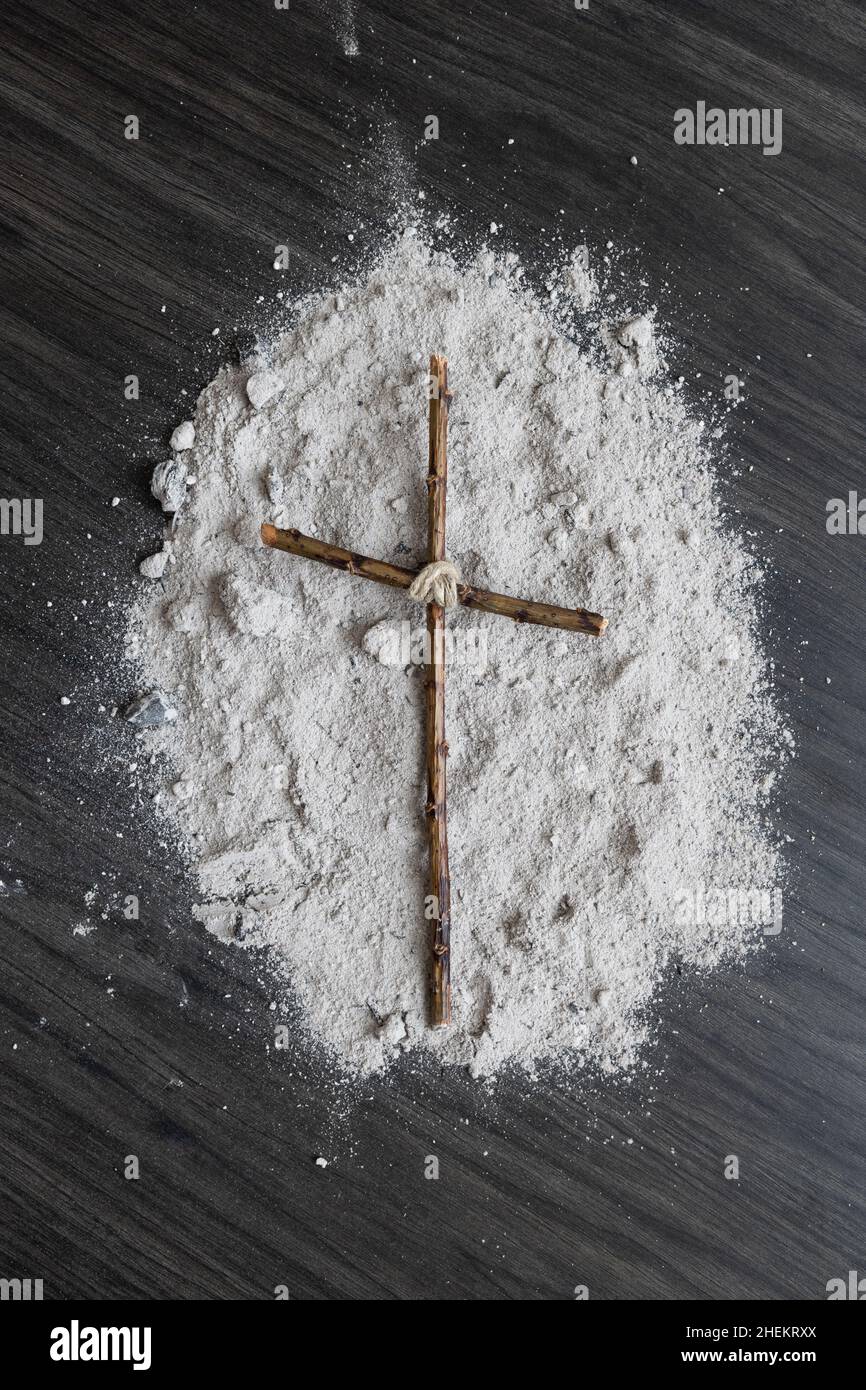 Simple wood cross on a bed or pile of ashes all on a dark wood ...