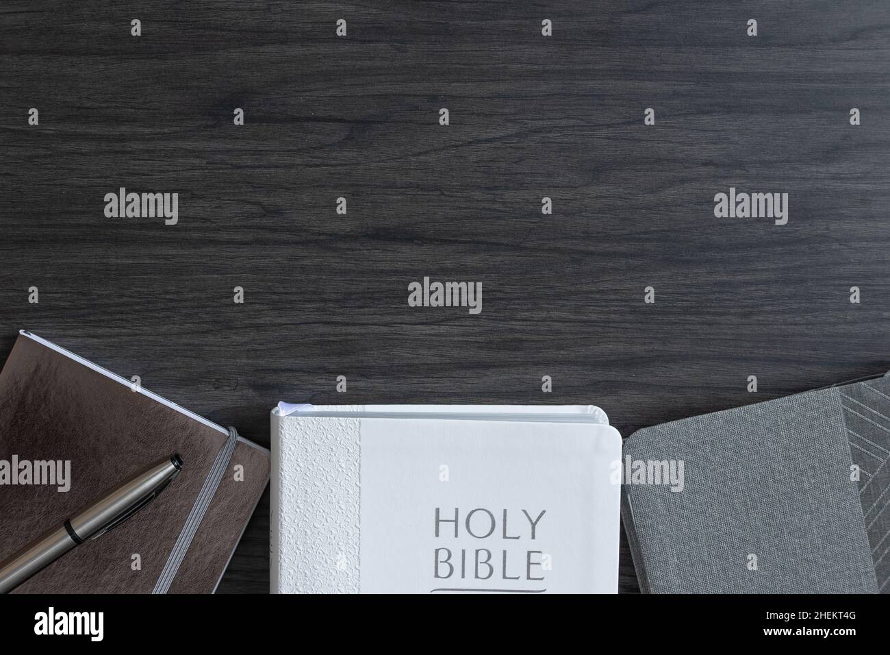 Border of white bible and grey journals on a dark wood background with ...