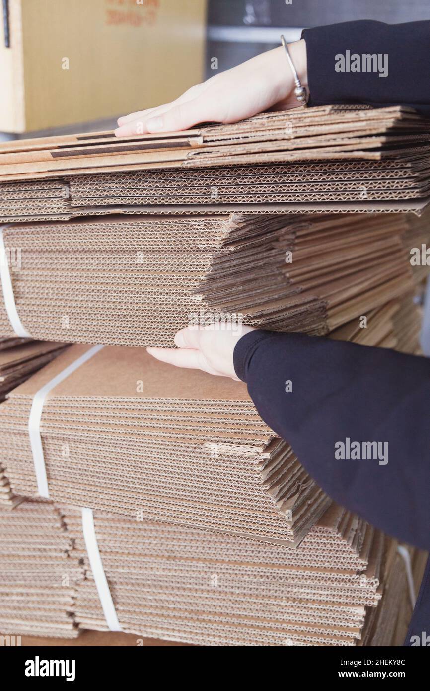 Woman taking folded stacks of corrugated cardboards for packing in ...