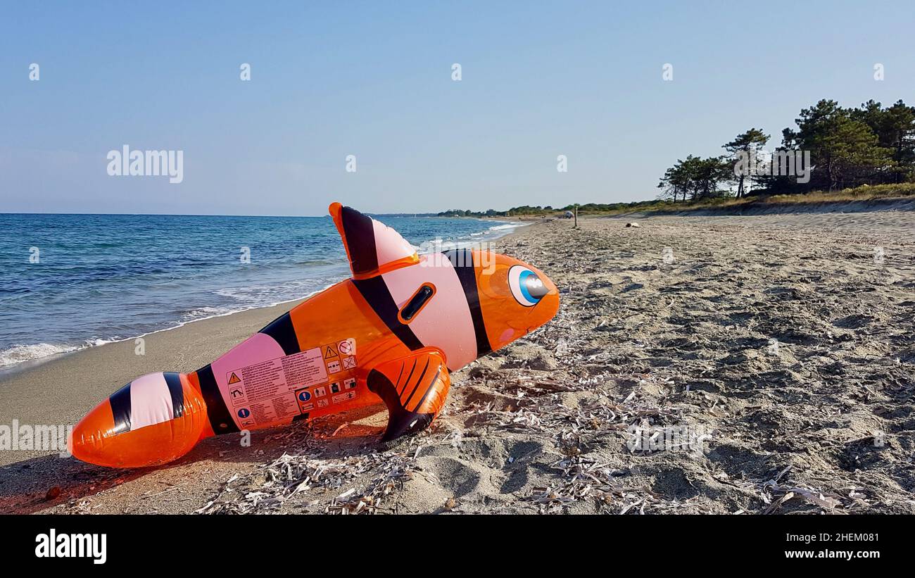 Inflatable orange fish on deserted sandy beach. Summer holiday concept ...