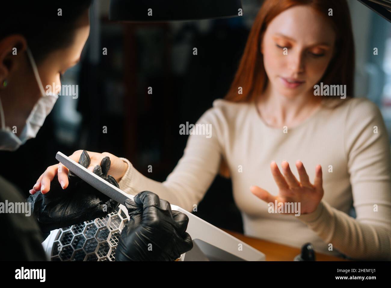 View from back to young woman client examining treated nails and ...