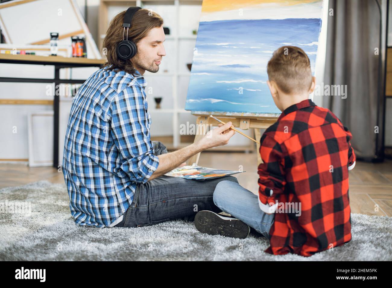 Young caucasian father and his little son sitting together on floor an ...