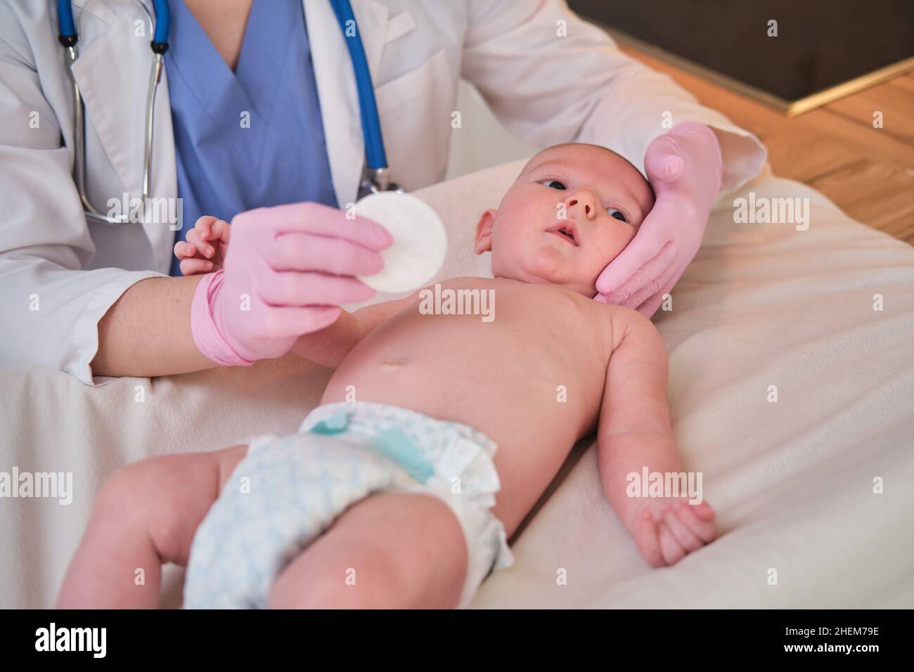 Doctor performs hygiene of the newborn baby nose and eyes with a cotton ...