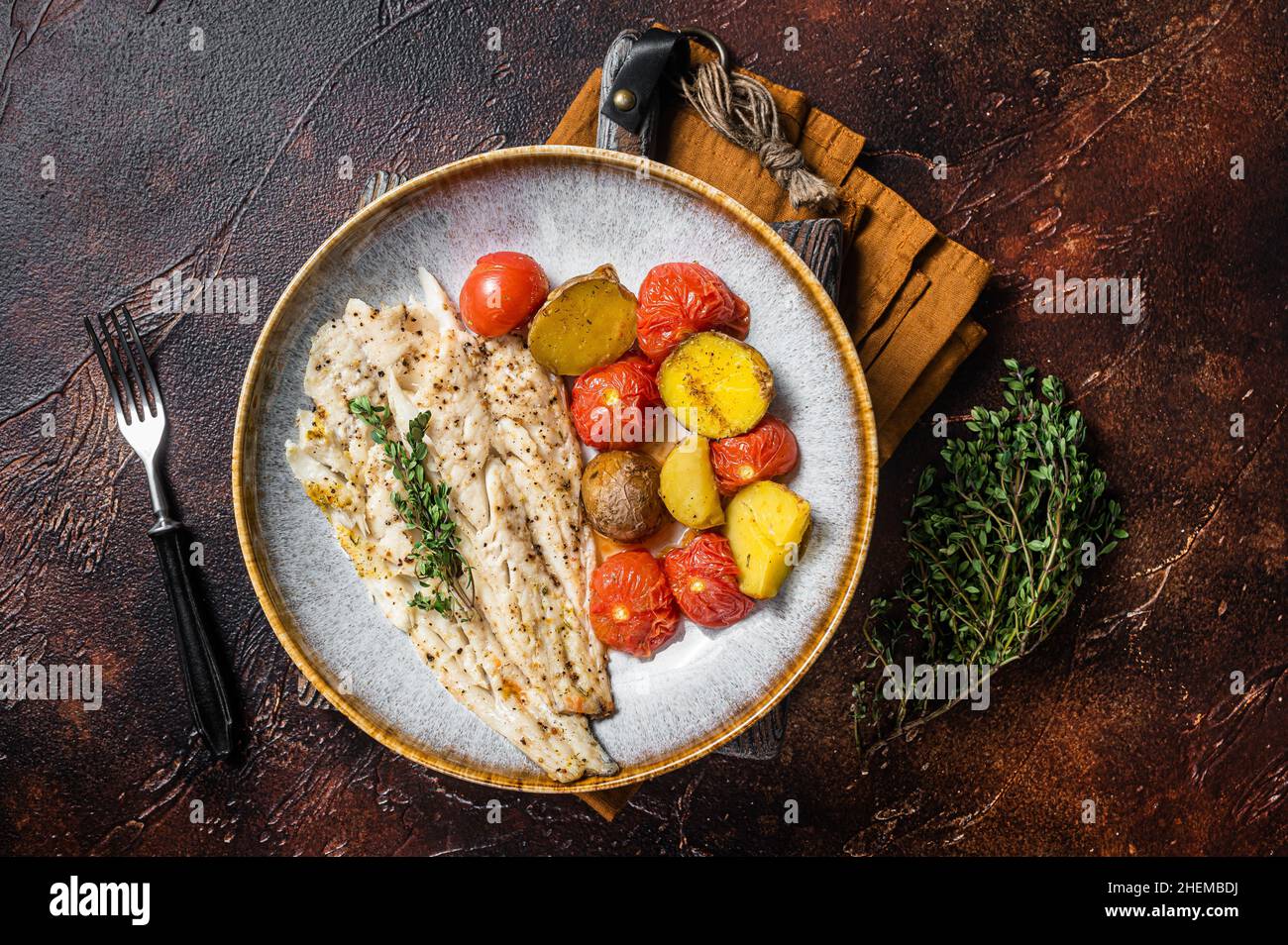 Roasted Pollock fish fillet in plate with garnish tomato and potato ...
