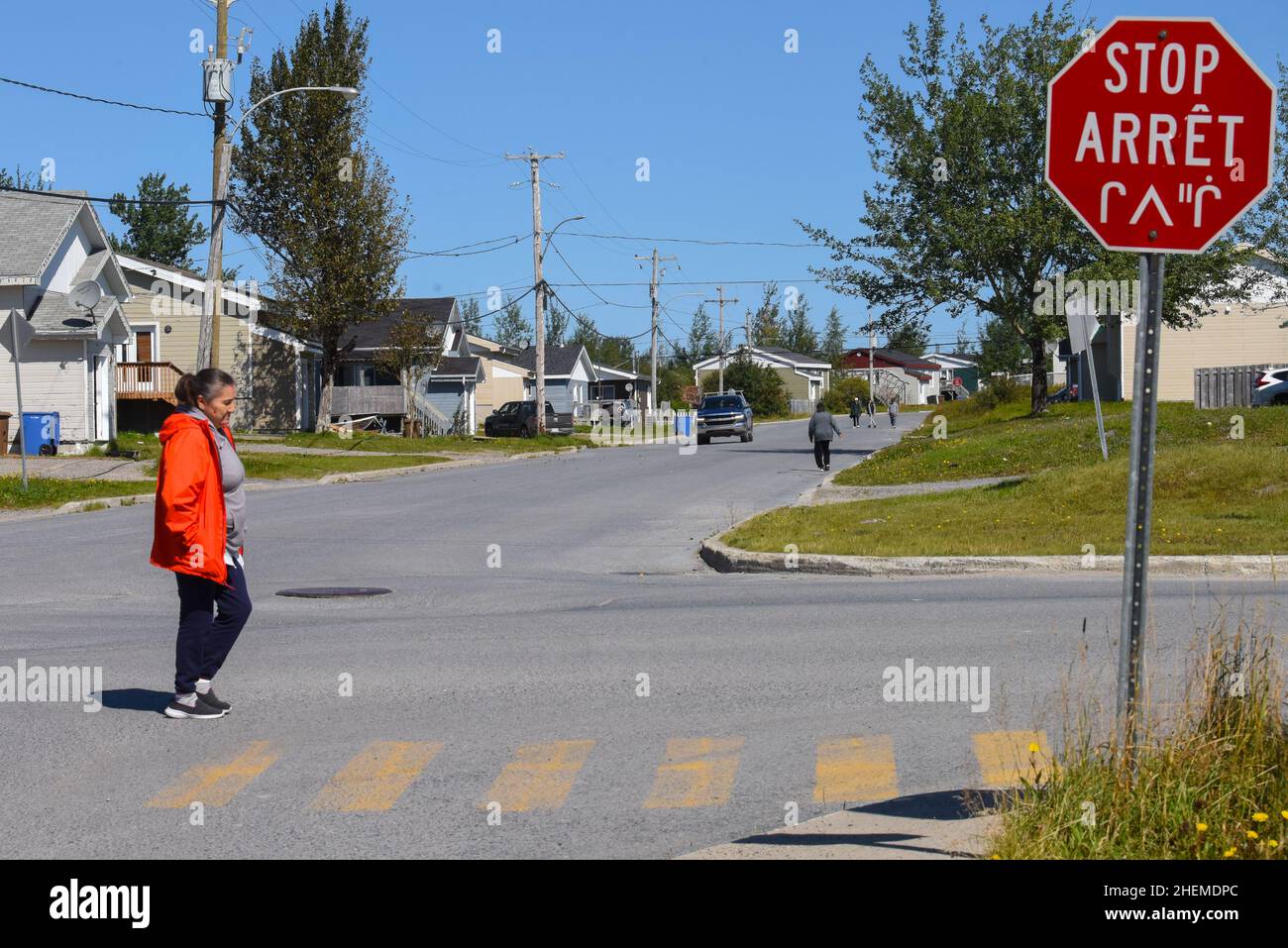 Indigenous Cree woman walking in front of stop sign in three languages ...