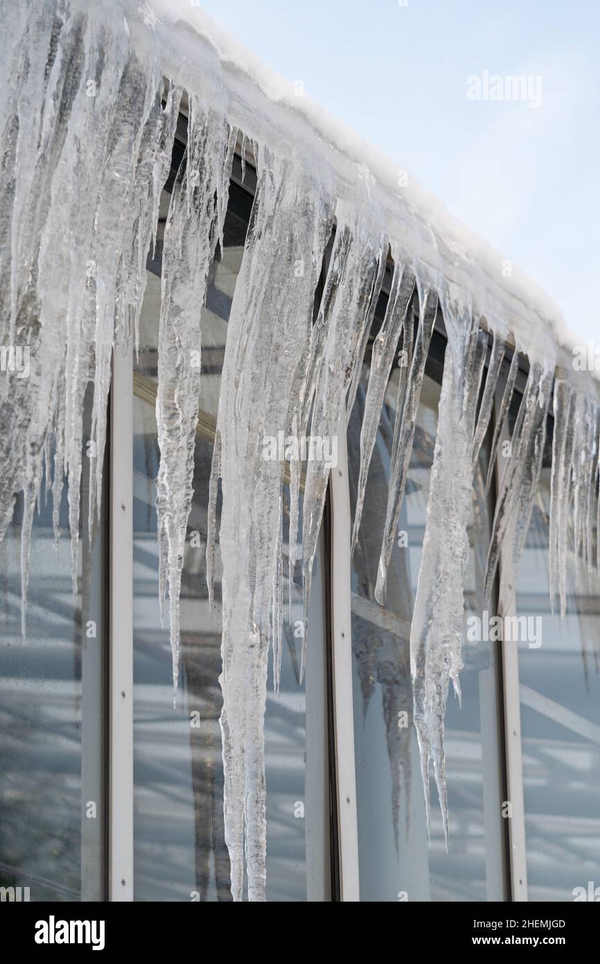 Icicles hang from roof and wall in winter. Frozen water from melting ...
